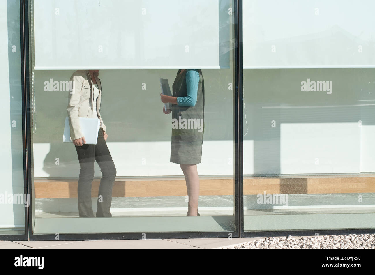 two women talking partly hidden behind screen Stock Photo - Alamy