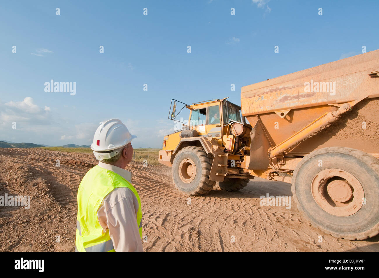 construction worker looking at earth moving truck Stock Photo - Alamy