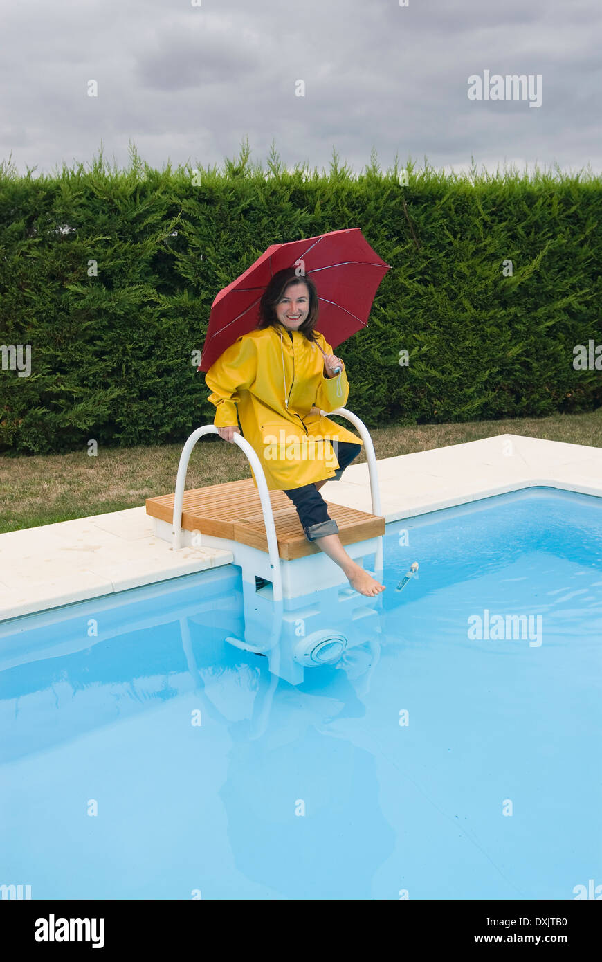 woman in rainwear tipping toe into swimming pool Stock Photo - Alamy