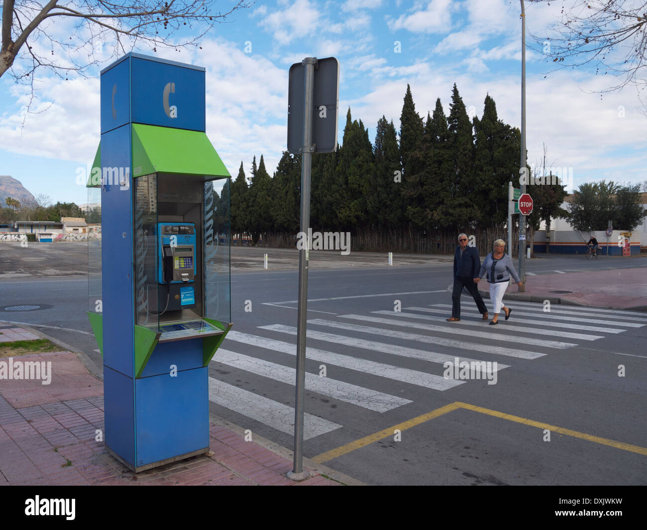 Public telephone with a pedestrian crossing and people crossing in ...