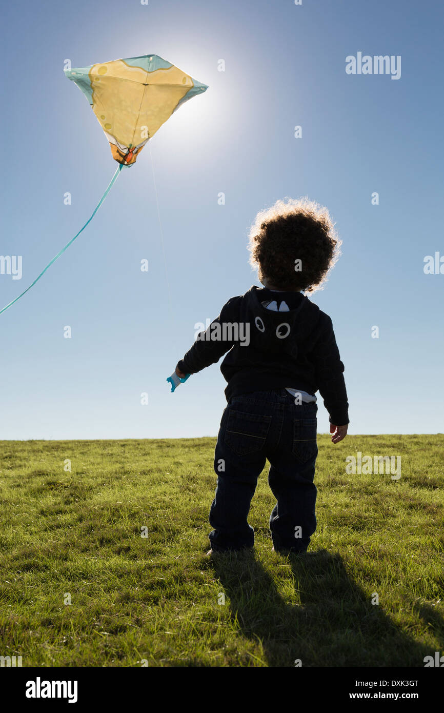 Mixed race boy watching kite flying against blue sky Stock Photo - Alamy
