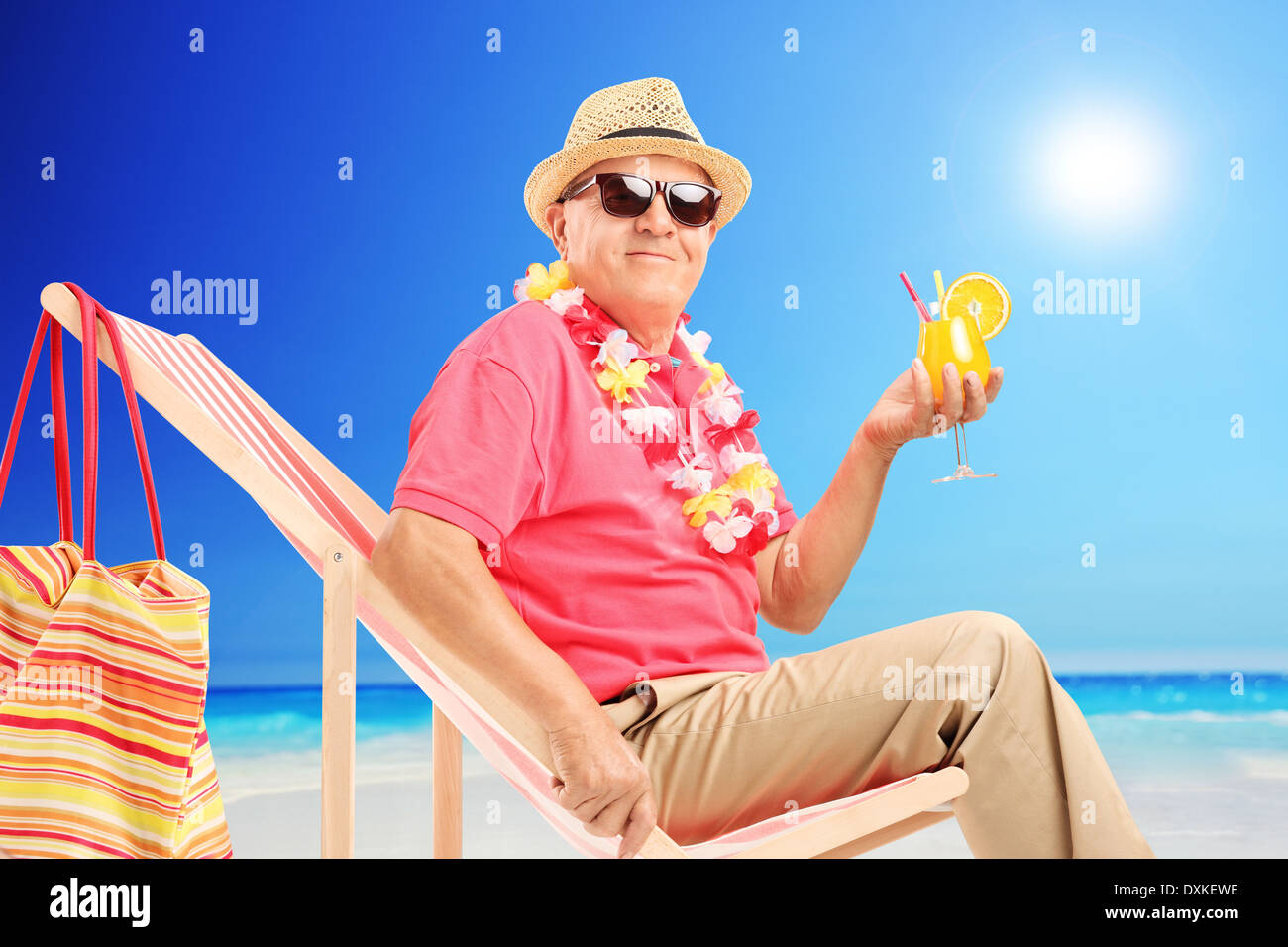 Mature man sitting on sun lounger and drinking cocktail on a sunny ...