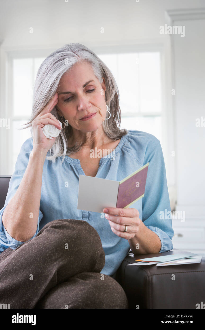 Serious Caucasian woman reading card on sofa Stock Photo - Alamy