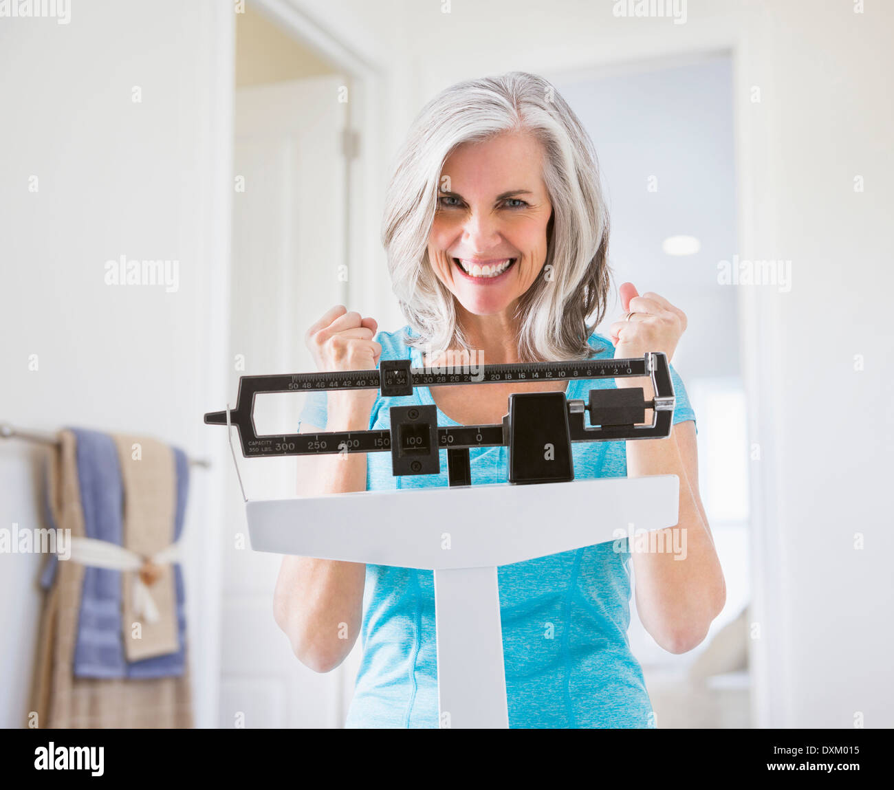 Excited Caucasian woman cheering on weight scale Stock Photo - Alamy