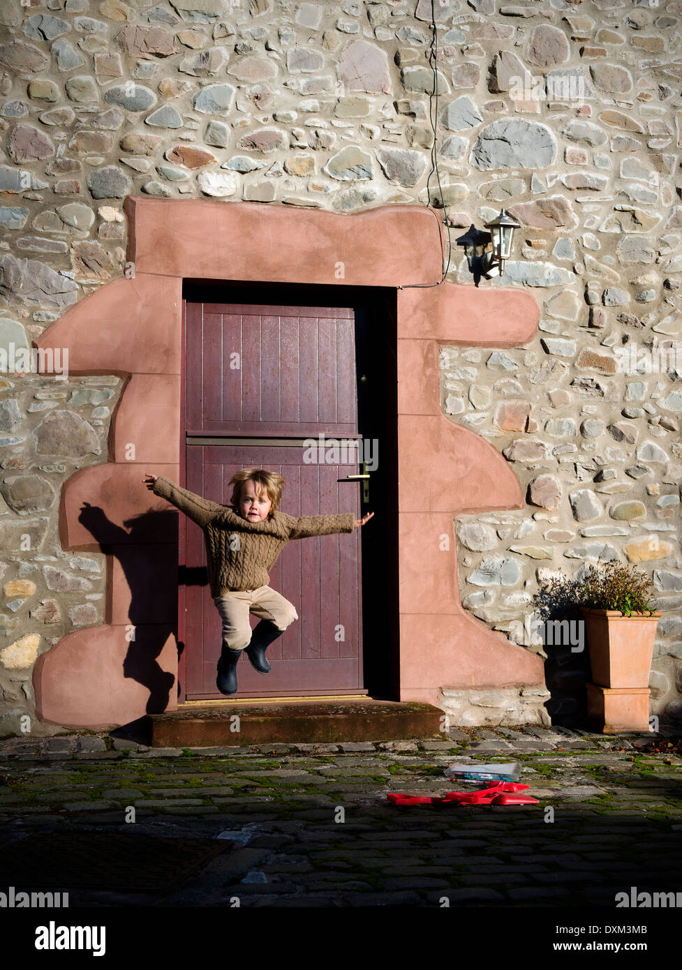 A young boy leaps from the doorstep outside a cottage during a family ...