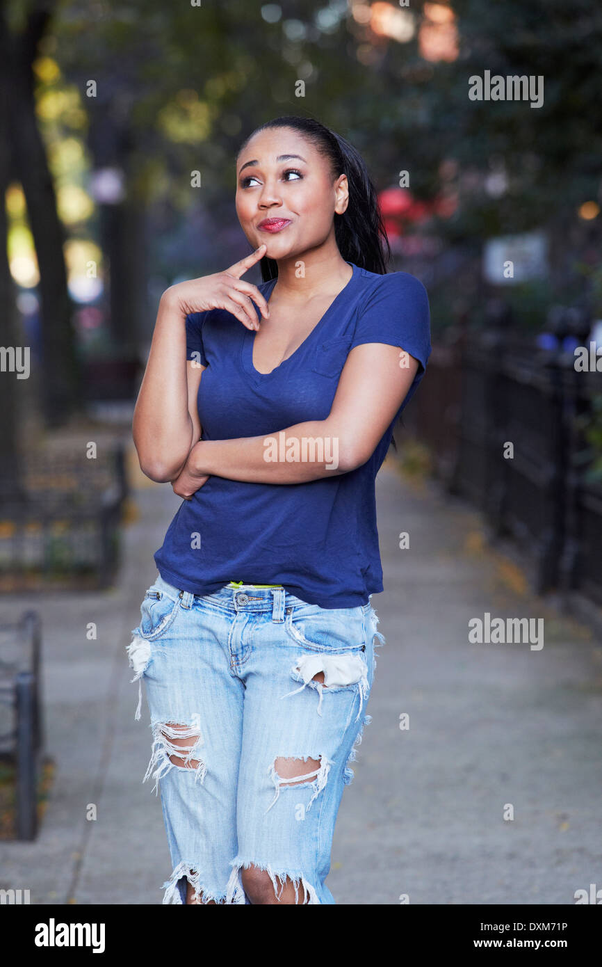 Mixed race woman thinking on urban sidewalk Stock Photo - Alamy