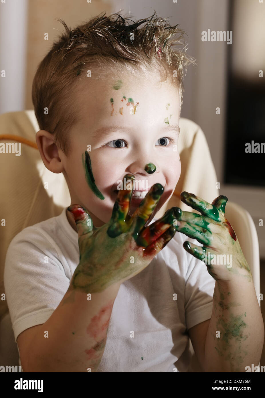 Excited handsome little boy playing with finger paints laughing as he ...