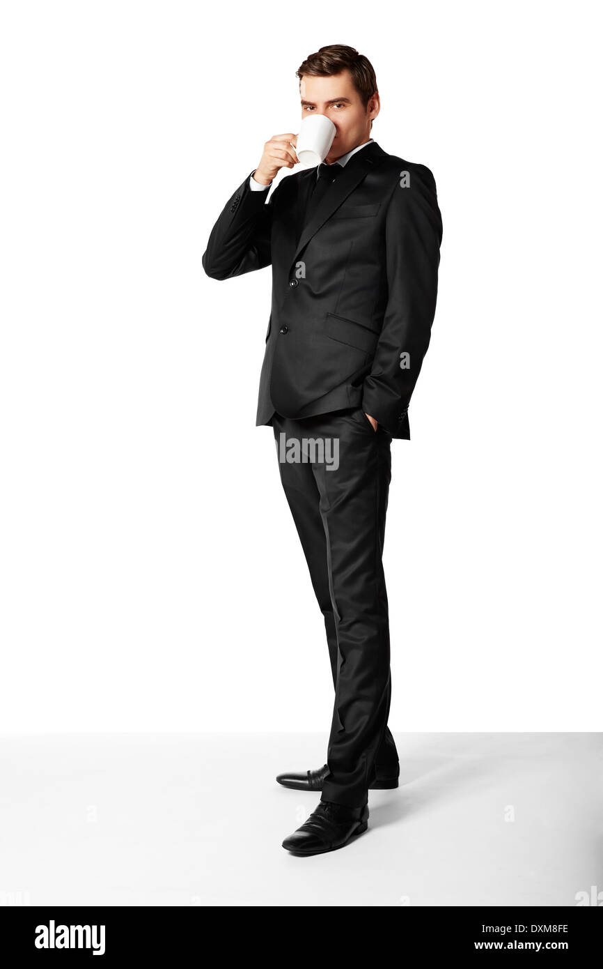 Businessman standing and drinking coffee against white background Stock ...