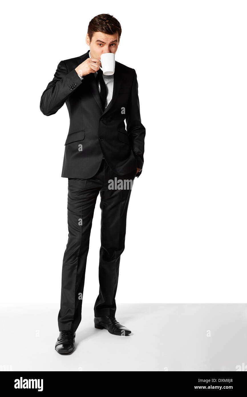 Businessman standing and drinking coffee against white background Stock ...