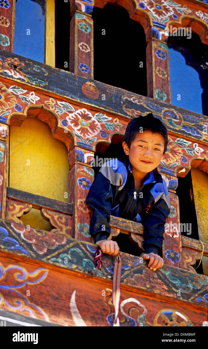 Bhutanese boy leaning out of carved and painted window, Bhutan Stock ...