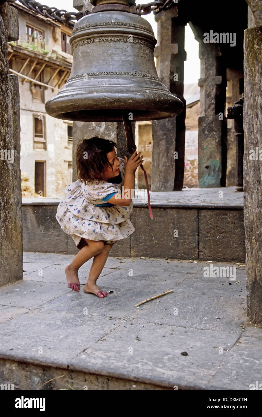 Nepali girl in white dress ringing a temple bell in Kathmandu, Nepal ...