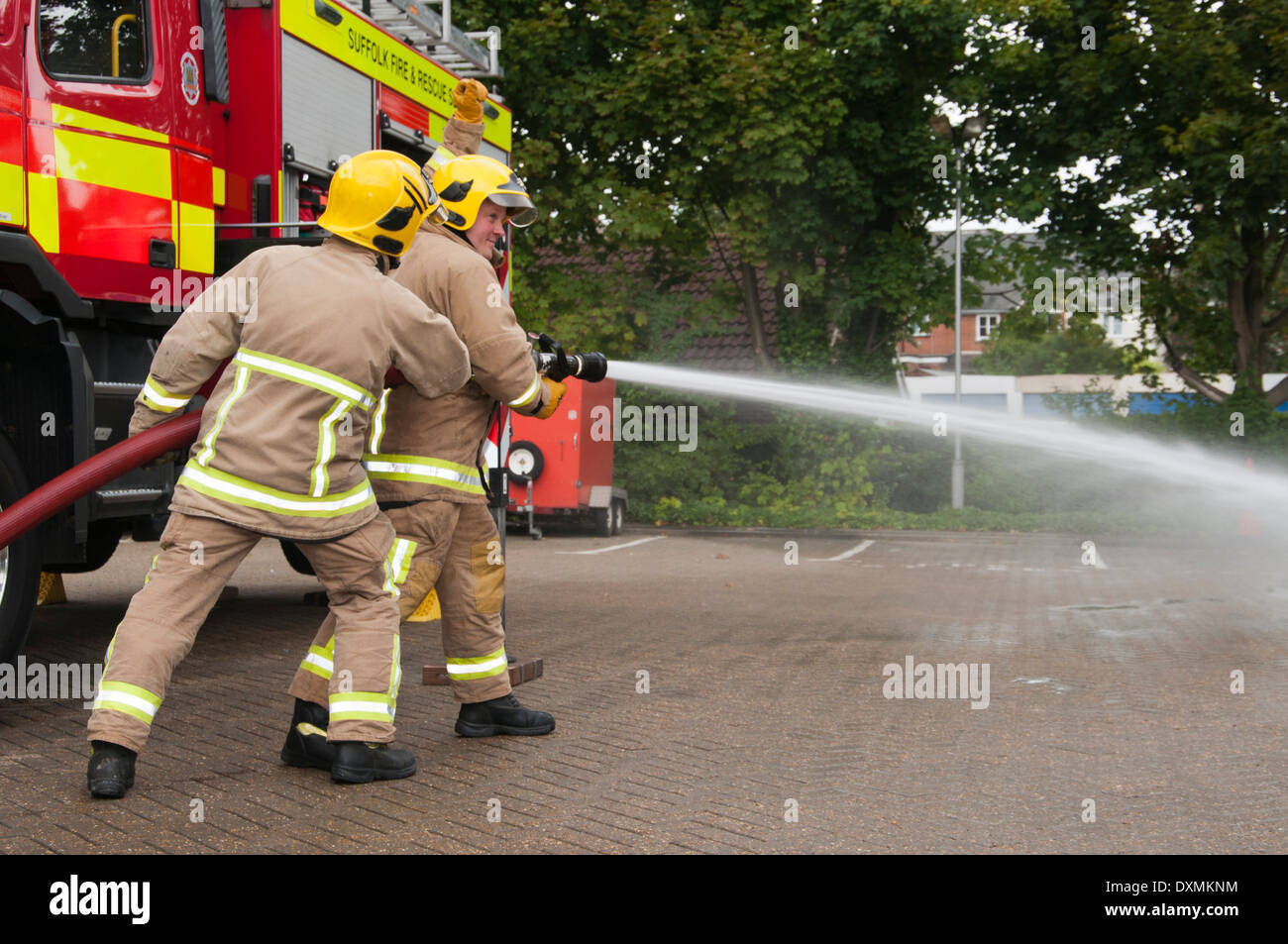 Two fire fighters demonstrating fire hose technique Stock Photo - Alamy
