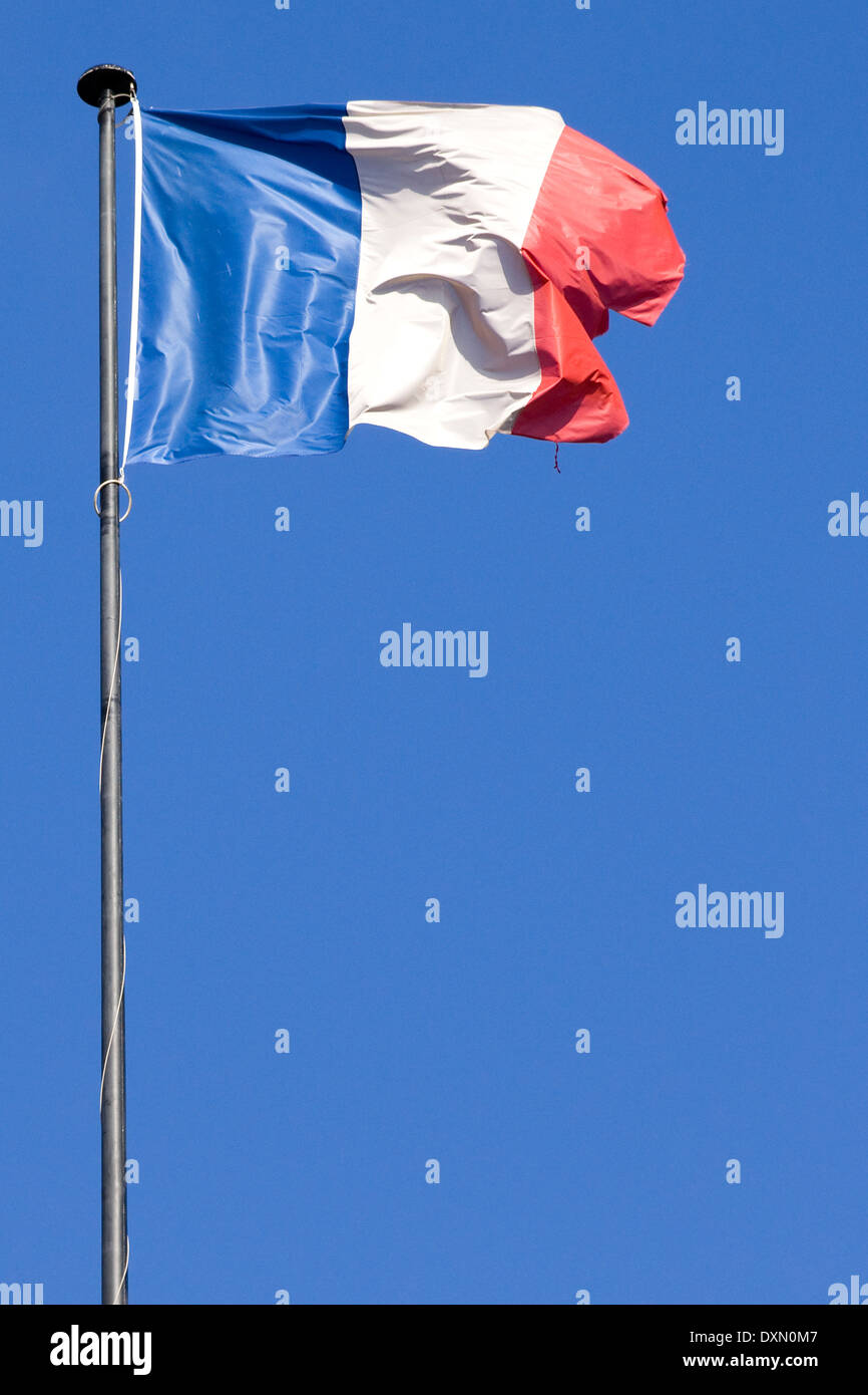 French Flag on a pole on top of a building against a blue sky Paris ...