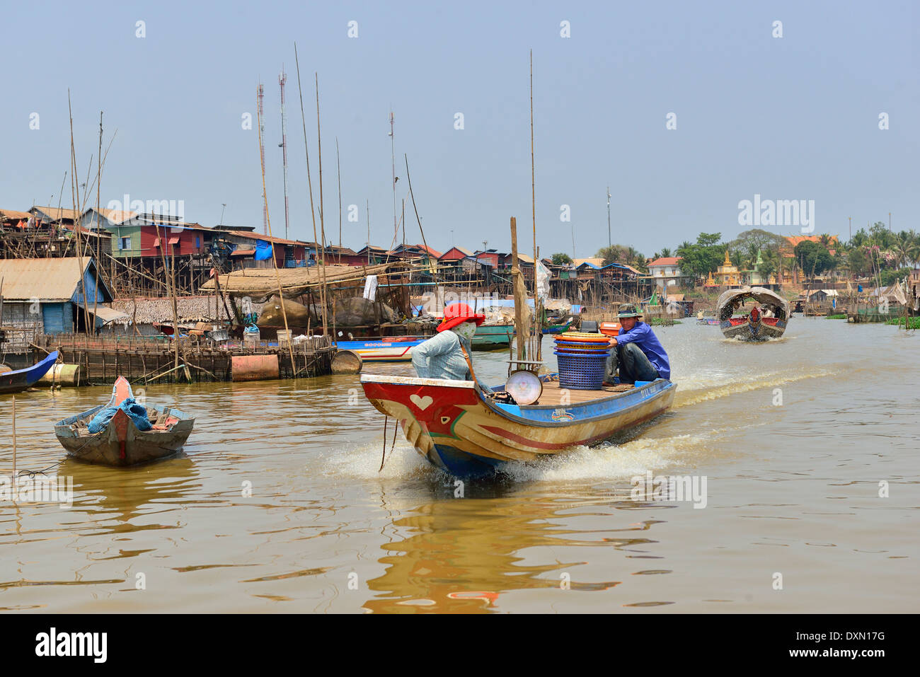 'Long-tail' speedboat ferrying produce along river with houses on ...