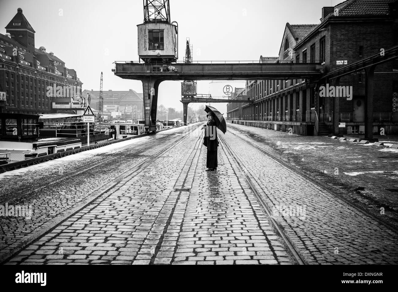 Germany, Berlin, woman with umbrella watching buildings at industrial ...