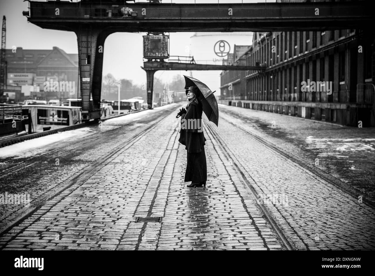 Germany, Berlin, woman with umbrella watching buildings at industrial ...