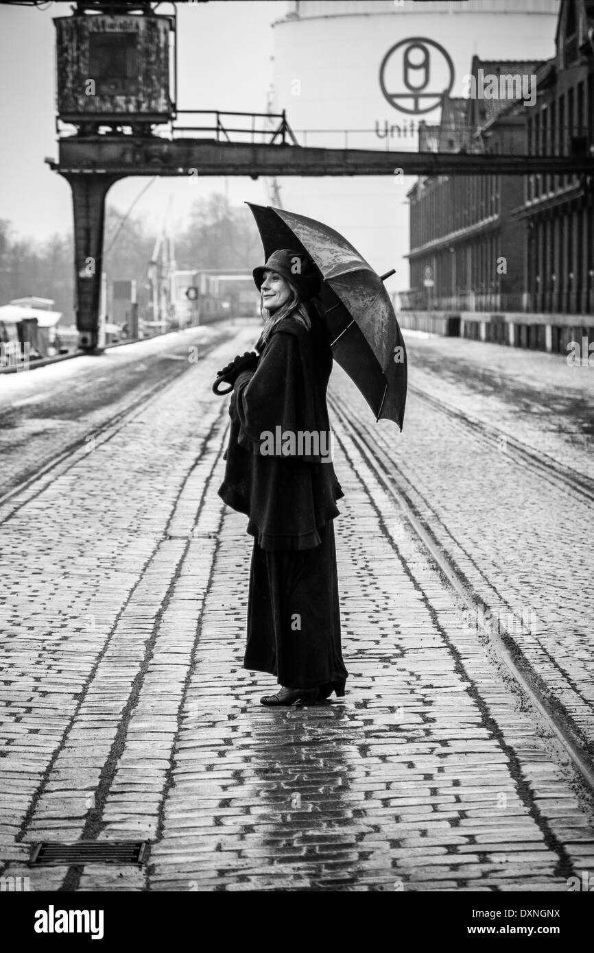Germany, Berlin, woman with umbrella watching buildings at industrial ...