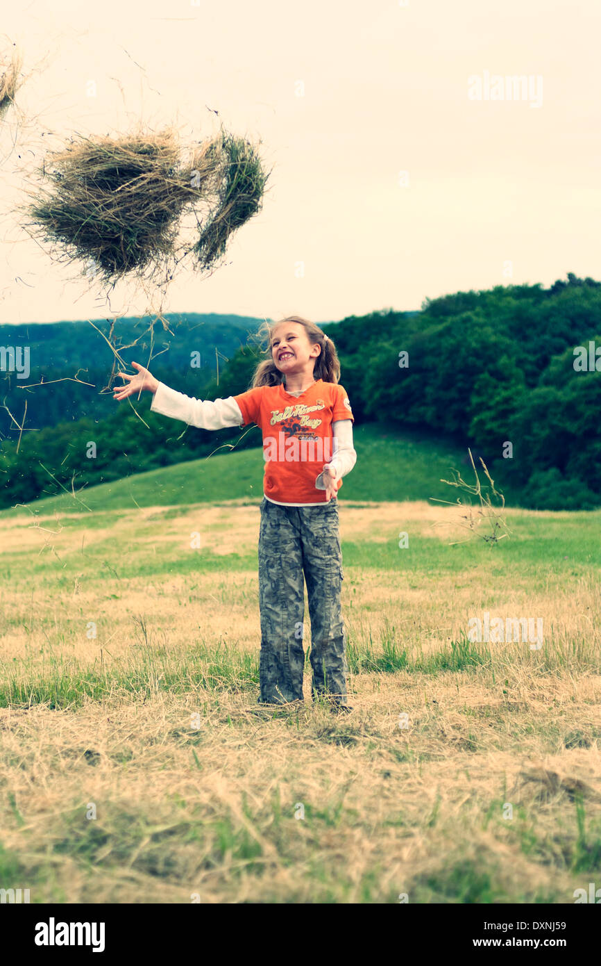 Little girl throwing hay Stock Photo - Alamy