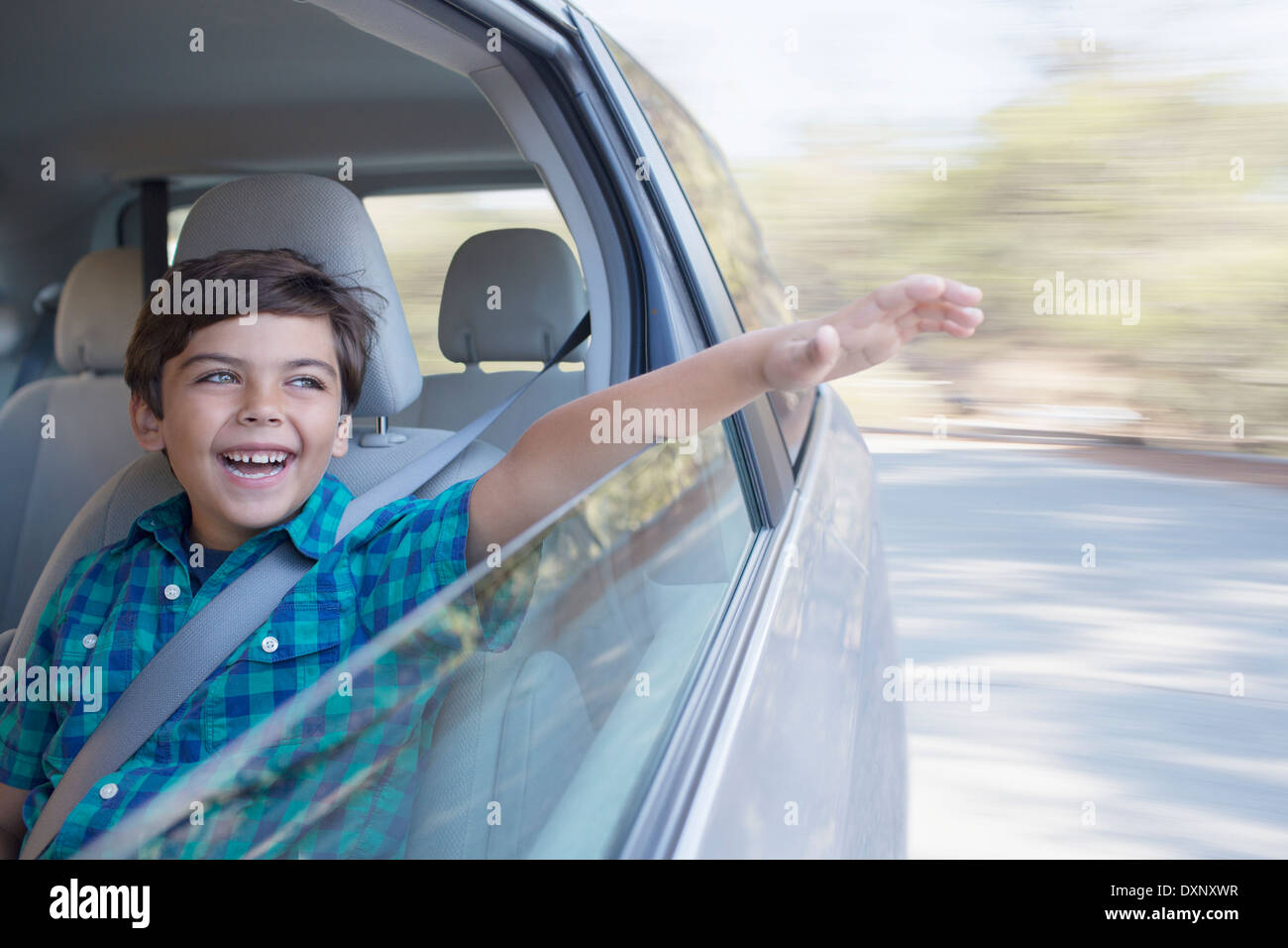 Happy boy sticking hand out window of car Stock Photo - Alamy