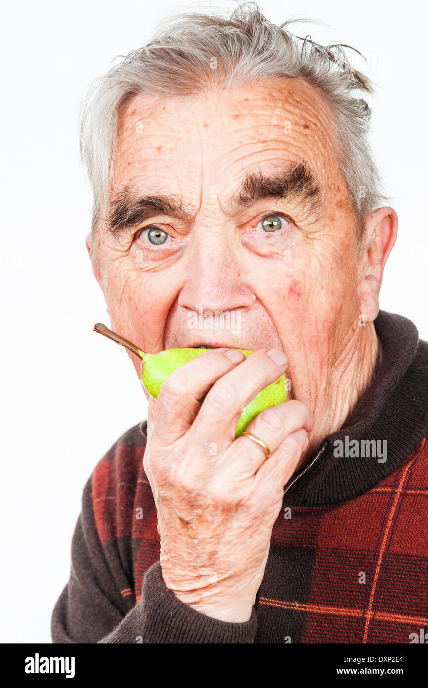 Portrait of senior man eating pear Stock Photo - Alamy