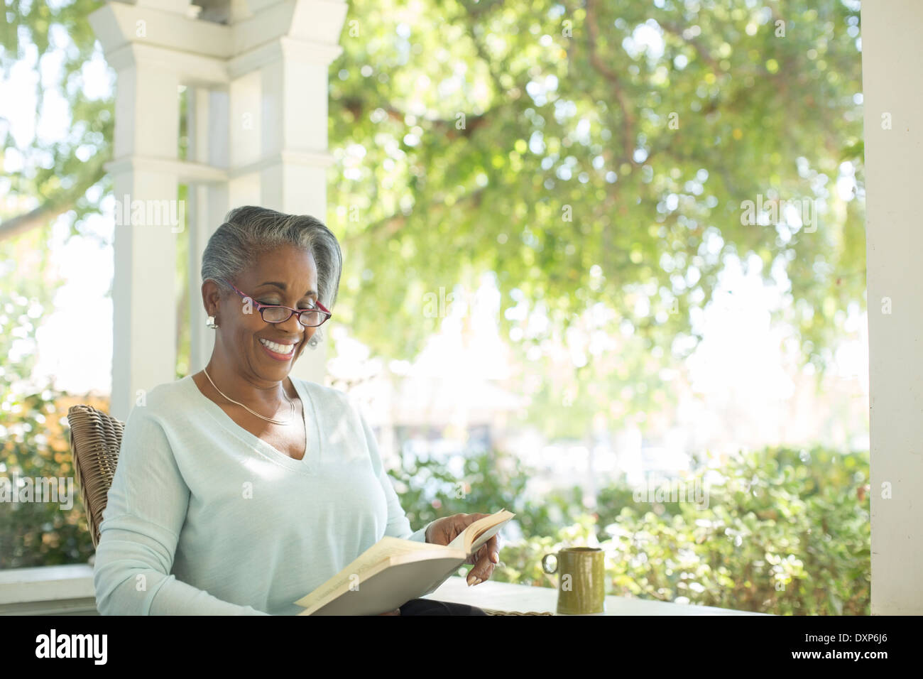 Happy senior woman reading book on porch Stock Photo - Alamy