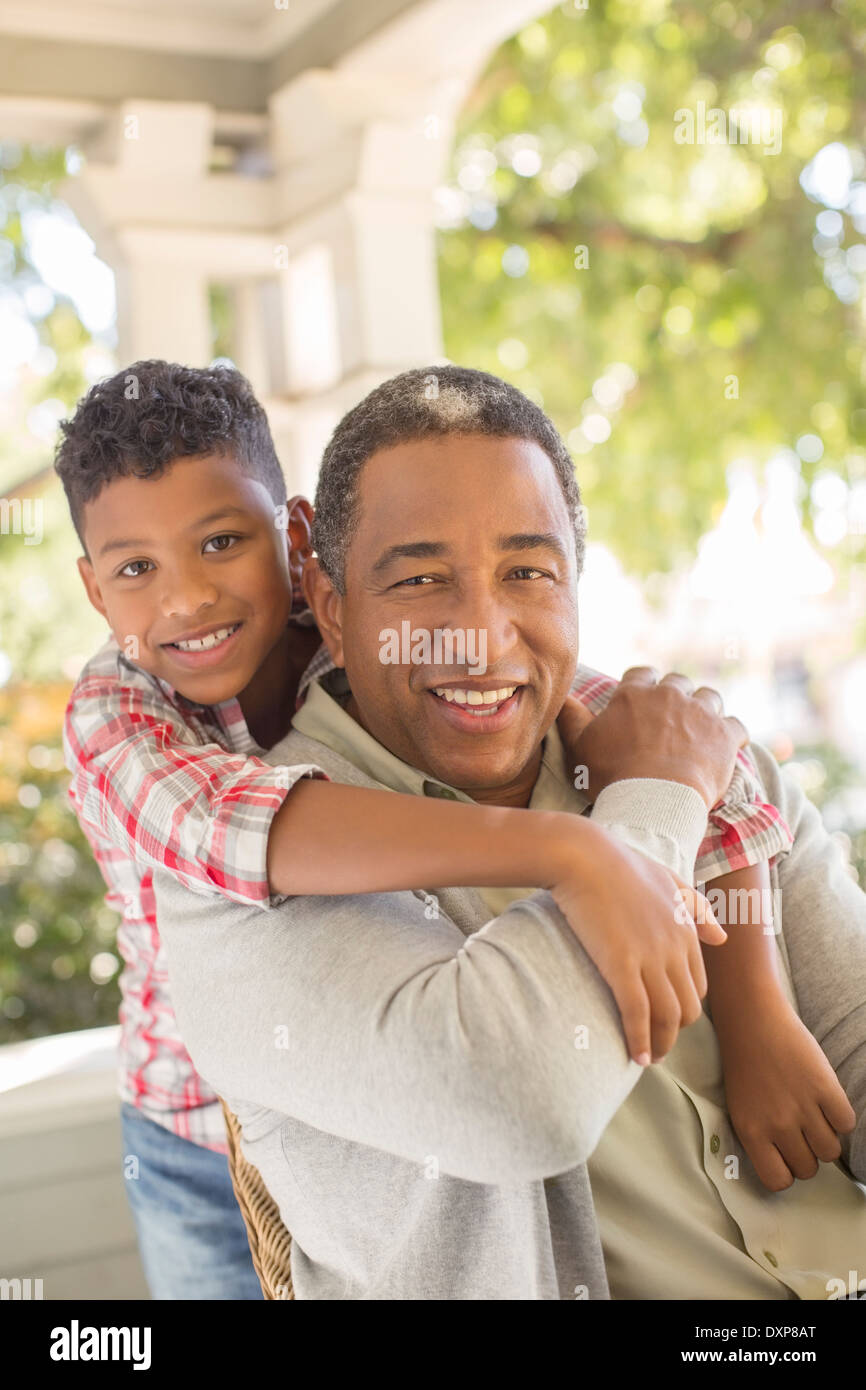 Close up portrait of smiling grandfather and grandson hugging on porch ...