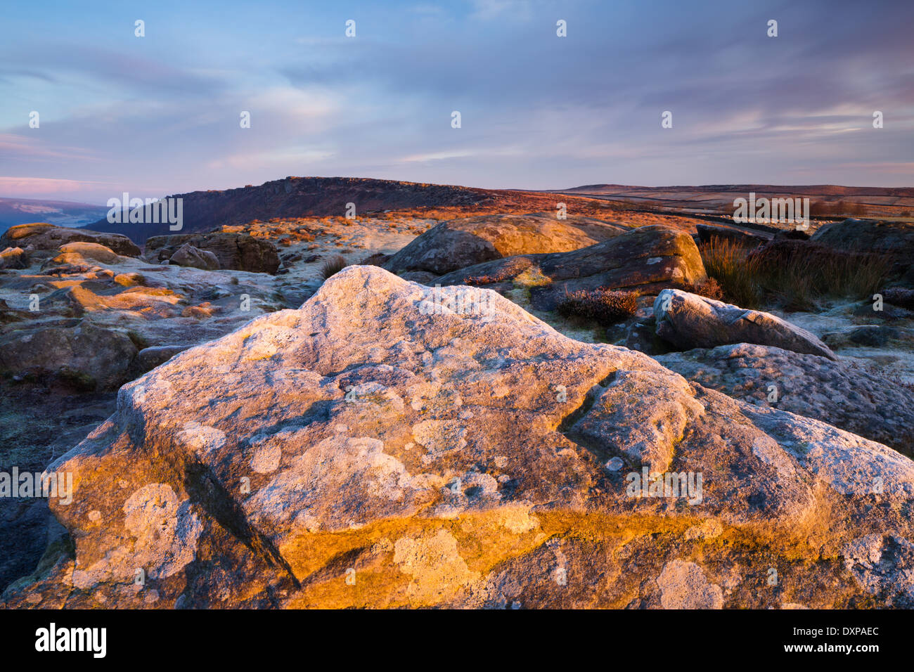 Dawn light adds some warmth to a triangular frosty boulder on Baslow ...