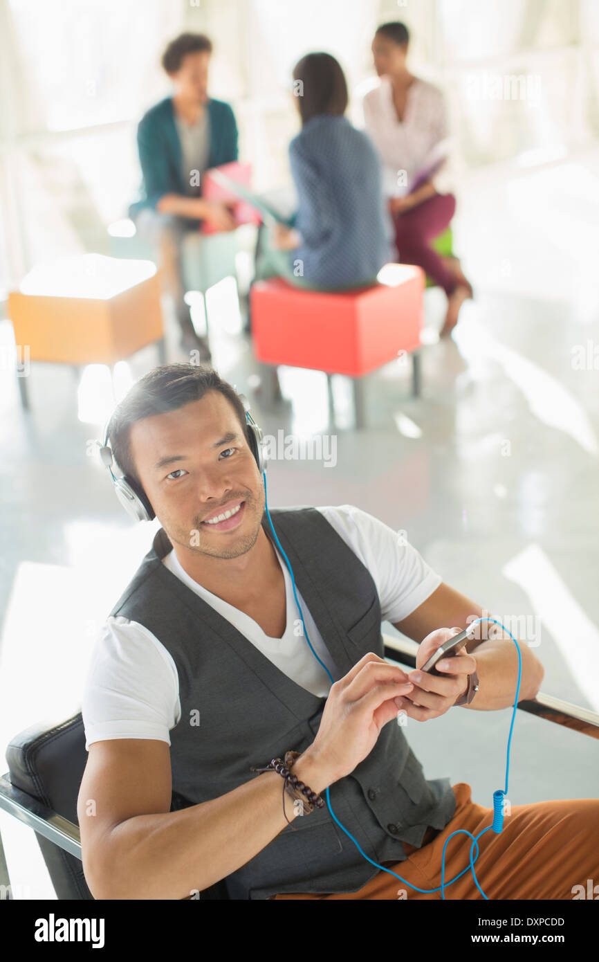 Portrait of casual businessman listening to music on headphones with ...