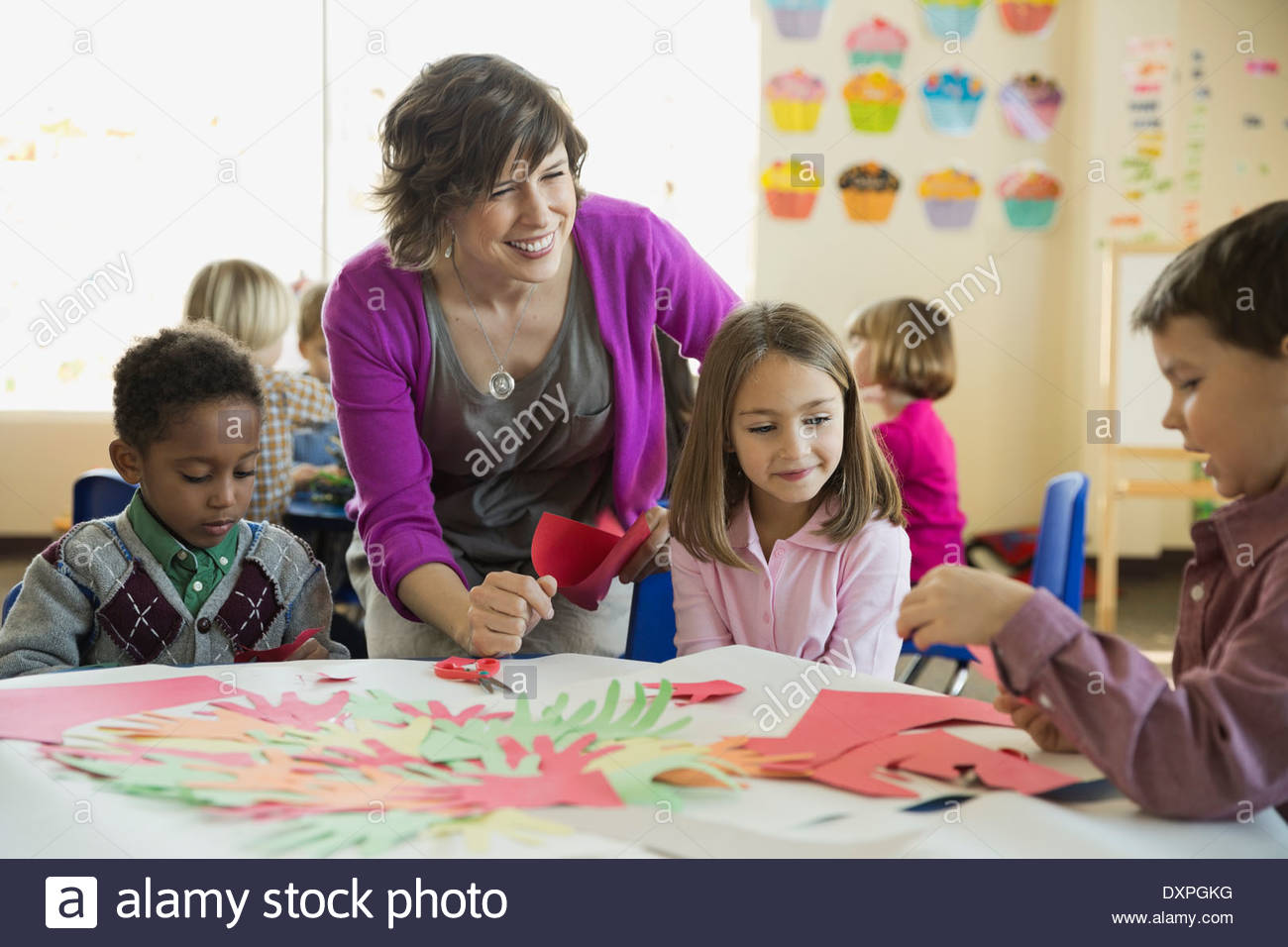 Smiling teacher with students in elementary class Stock Photo - Alamy