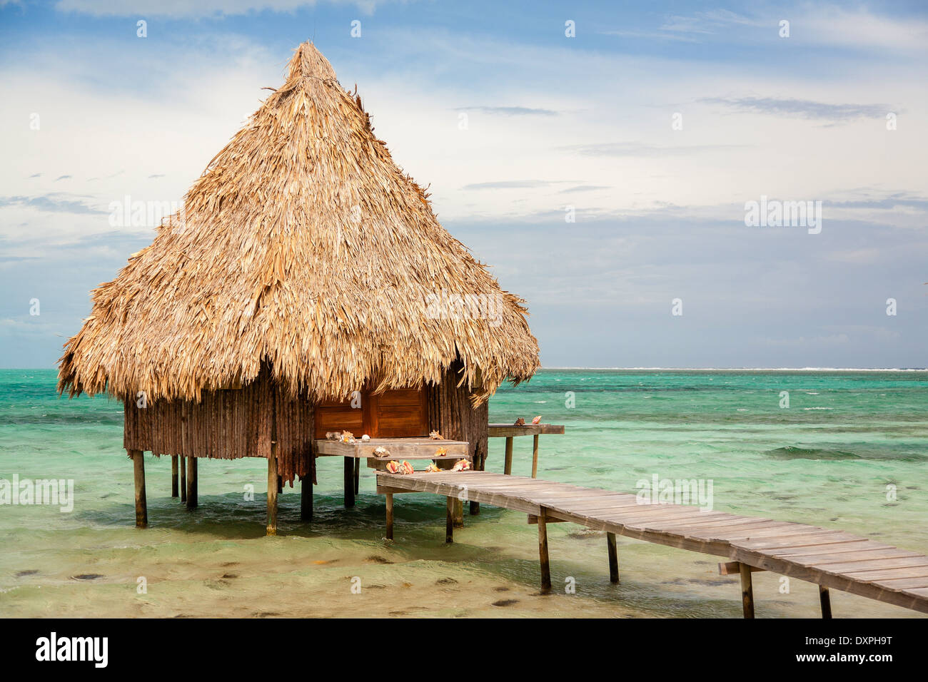 Palm thatched hut on stilts over a shallow lagoon on the coral island ...