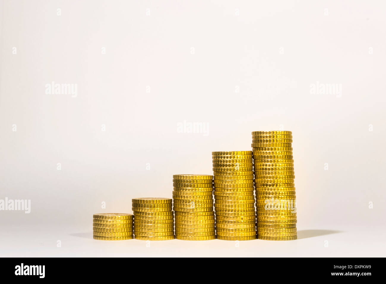 Yellow coins lined up from short to tall stacks with blank background ...