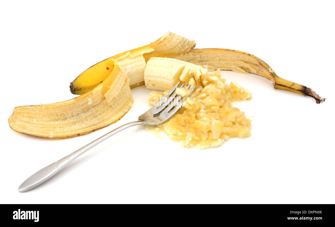 Mashing a peeled overripe banana with a fork, isolated on a white ...