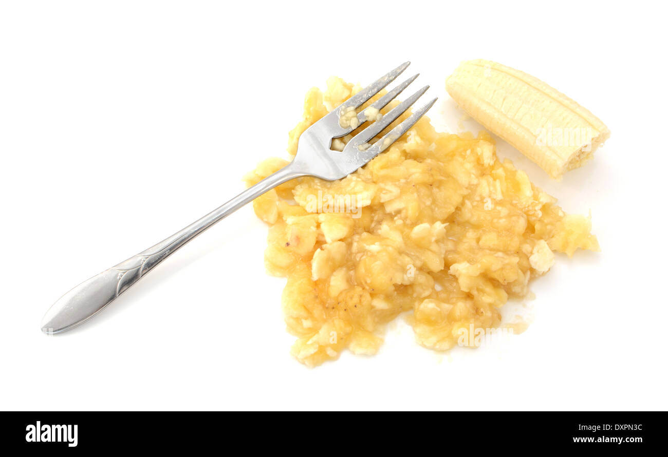 Ripe banana being mashed with a fork, isolated on a white background ...