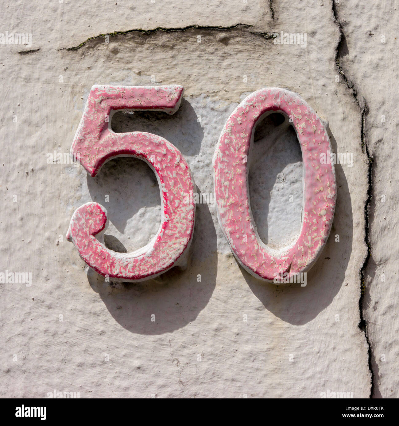 Red house number fifty next to a crack in the wall Stock Photo - Alamy