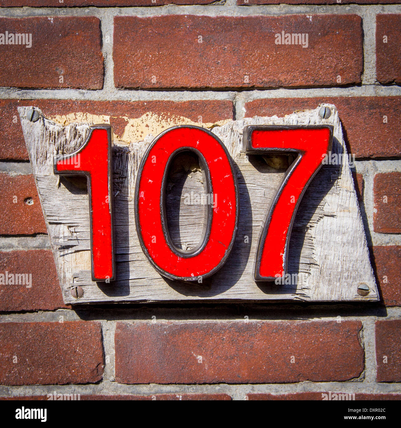 ceramic house number one hundred and seven on a weathered piece of wood ...