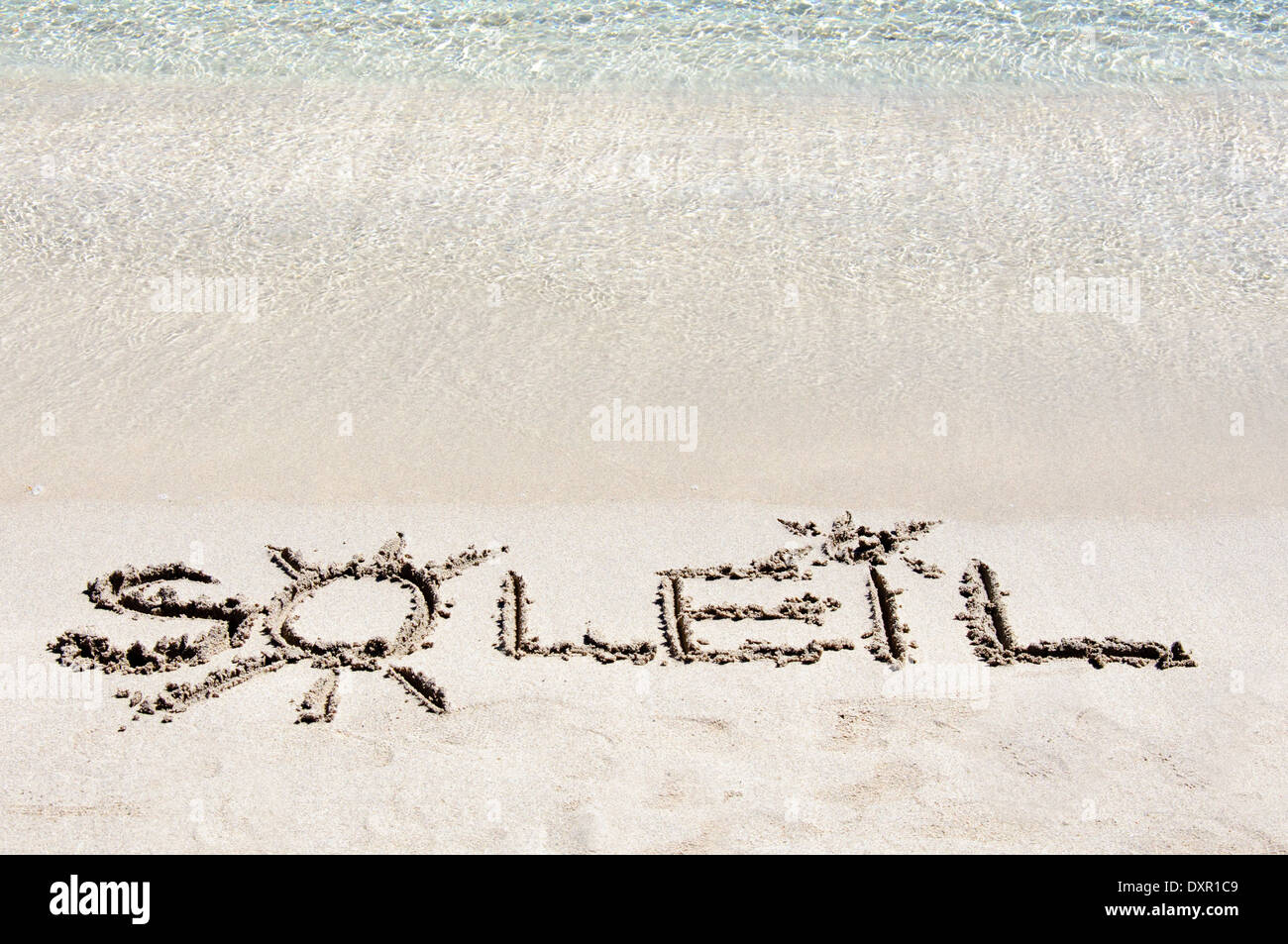 The Word "SOLEIL" Written on Sand on a beautiful beach, with blue waves ...