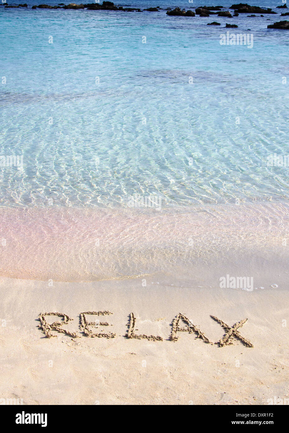 Relax word written in the sand, on a beautiful beach with clear blue ...