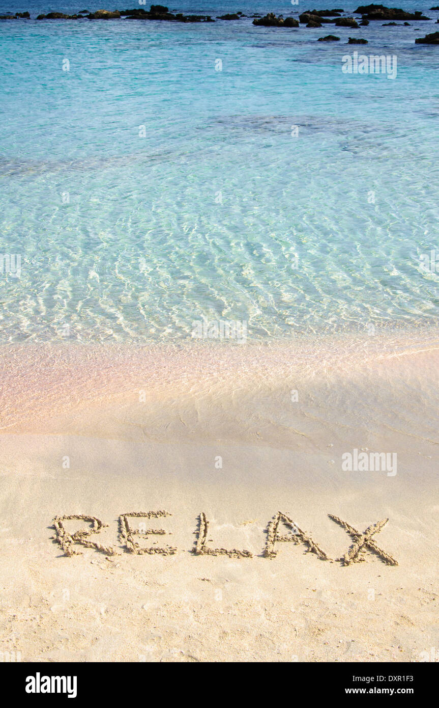 Relax word written in the sand, on a beautiful beach with clear blue ...