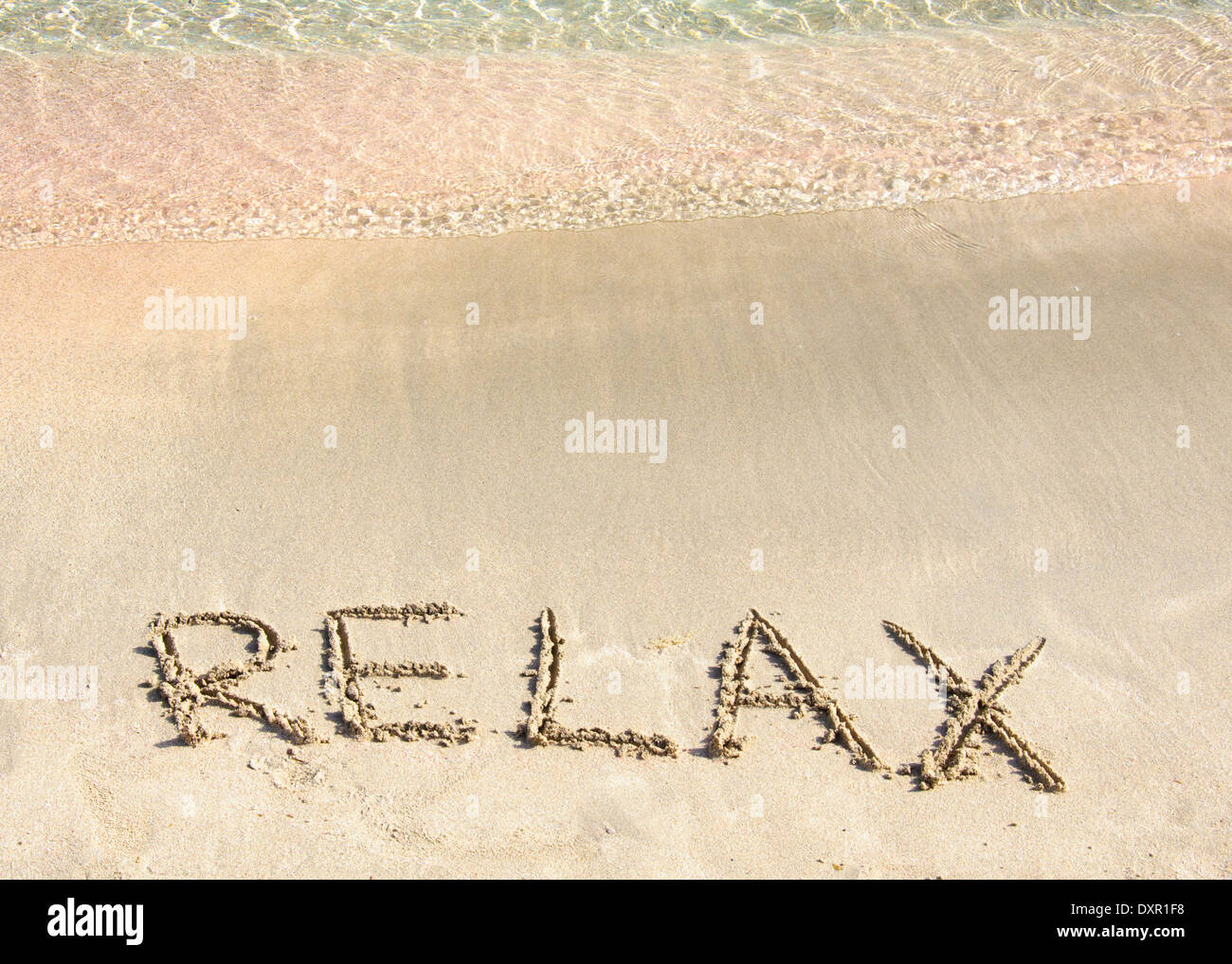 Relax word written in the sand, on a beautiful beach with clear blue ...