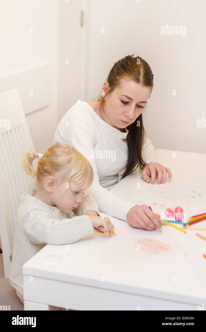 Little girl with mother drawing with colorful crayons at home Stock ...