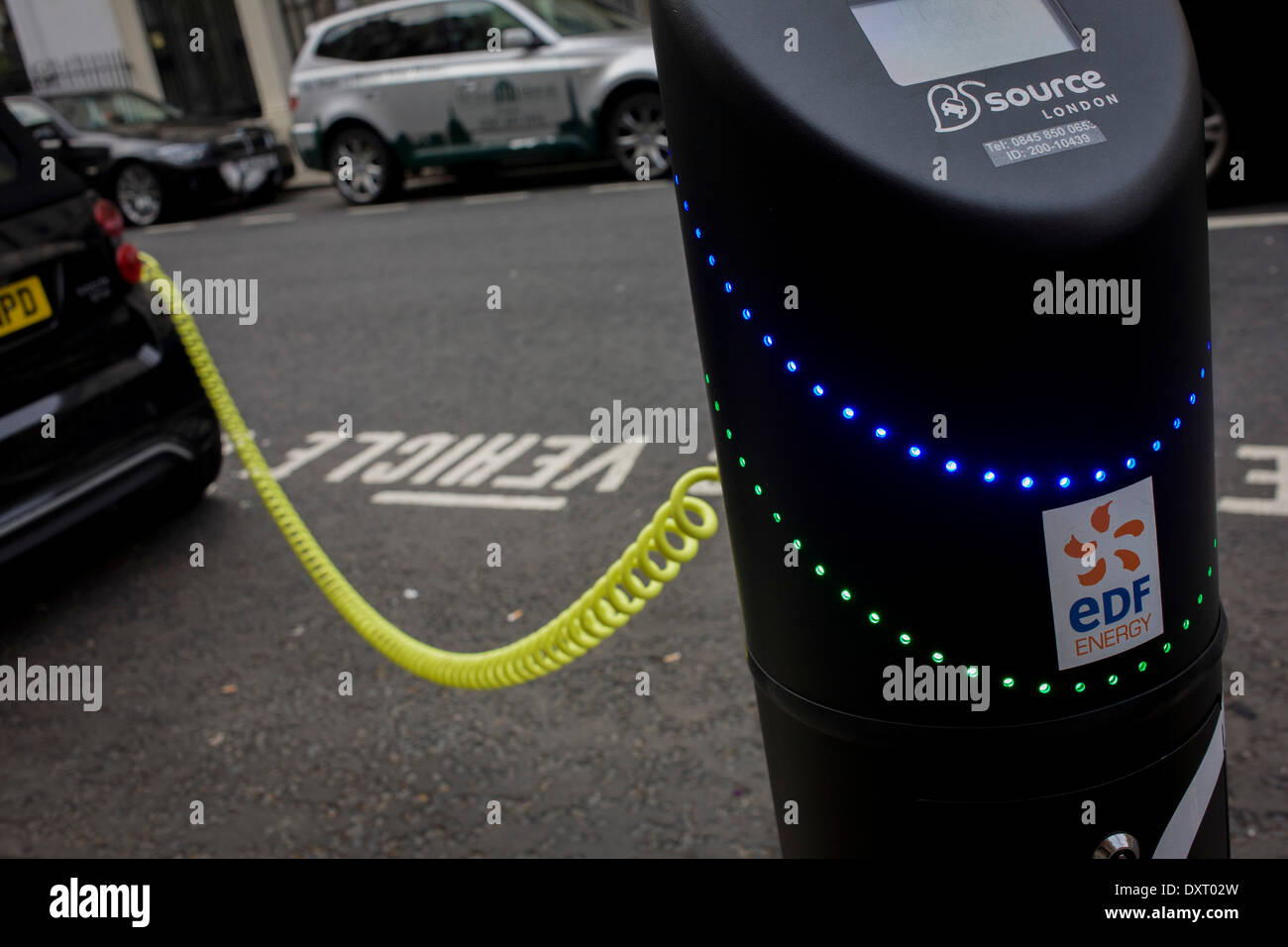 A parked Smart car recharges electric power at an EDF charging point in ...