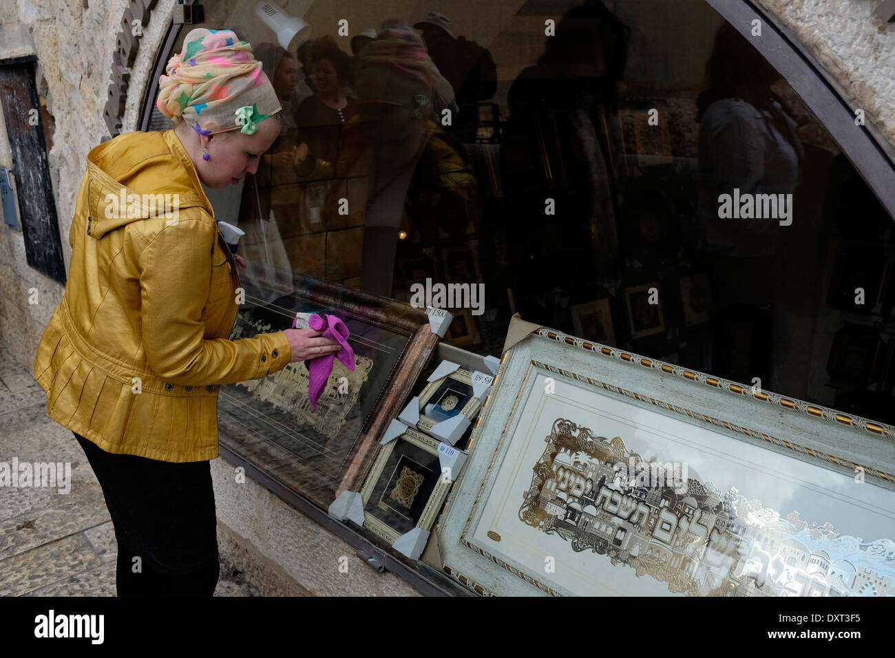 A young religious Jewish woman cleaning a window of a souvenir shop in ...