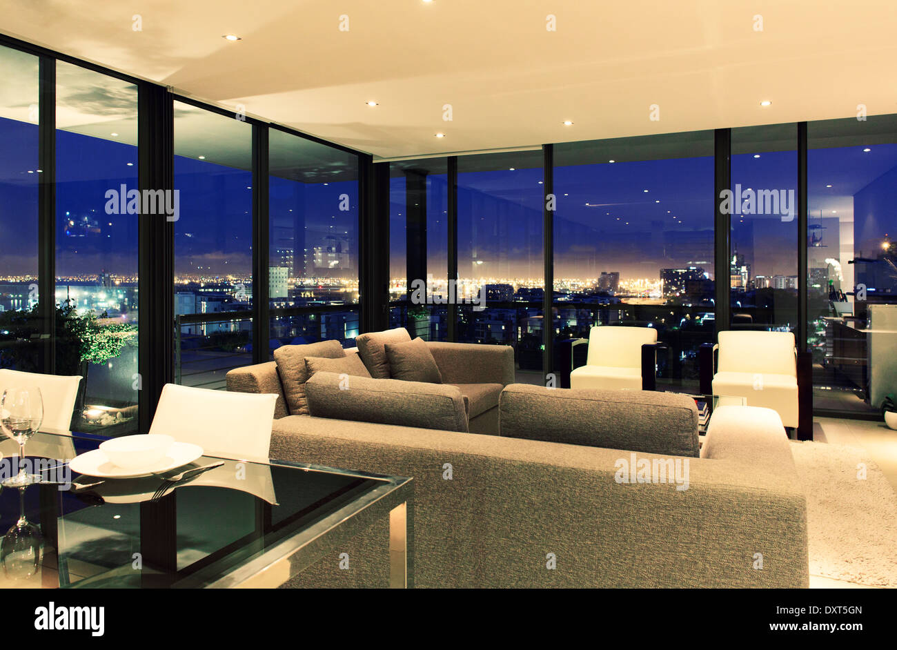 Illuminated modern living room overlooking city Stock Photo - Alamy