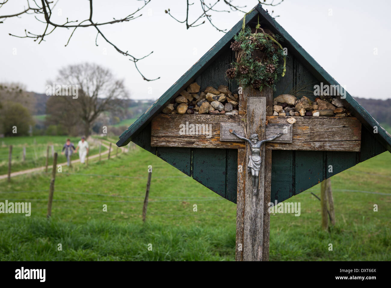 Crucifix in a landscape with walking people on a trail in the ...