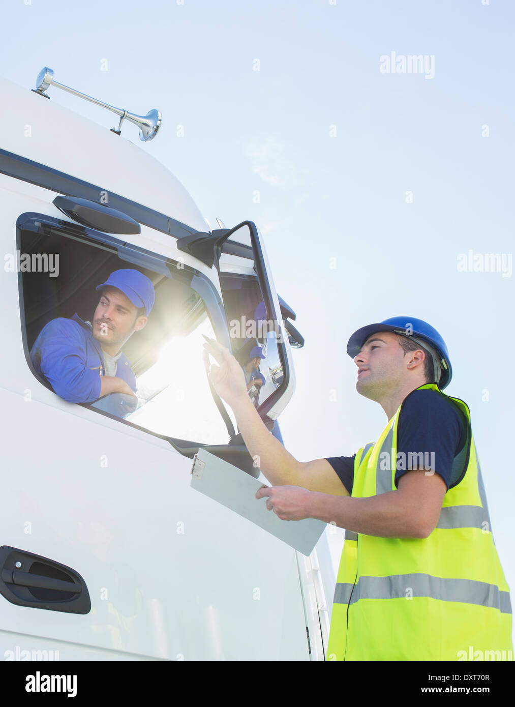 Worker with clipboard directing truck driver Stock Photo - Alamy