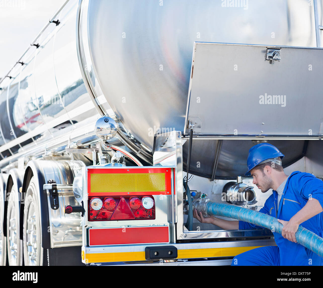 Worker attaching hose to back of stainless steel milk tanker Stock ...