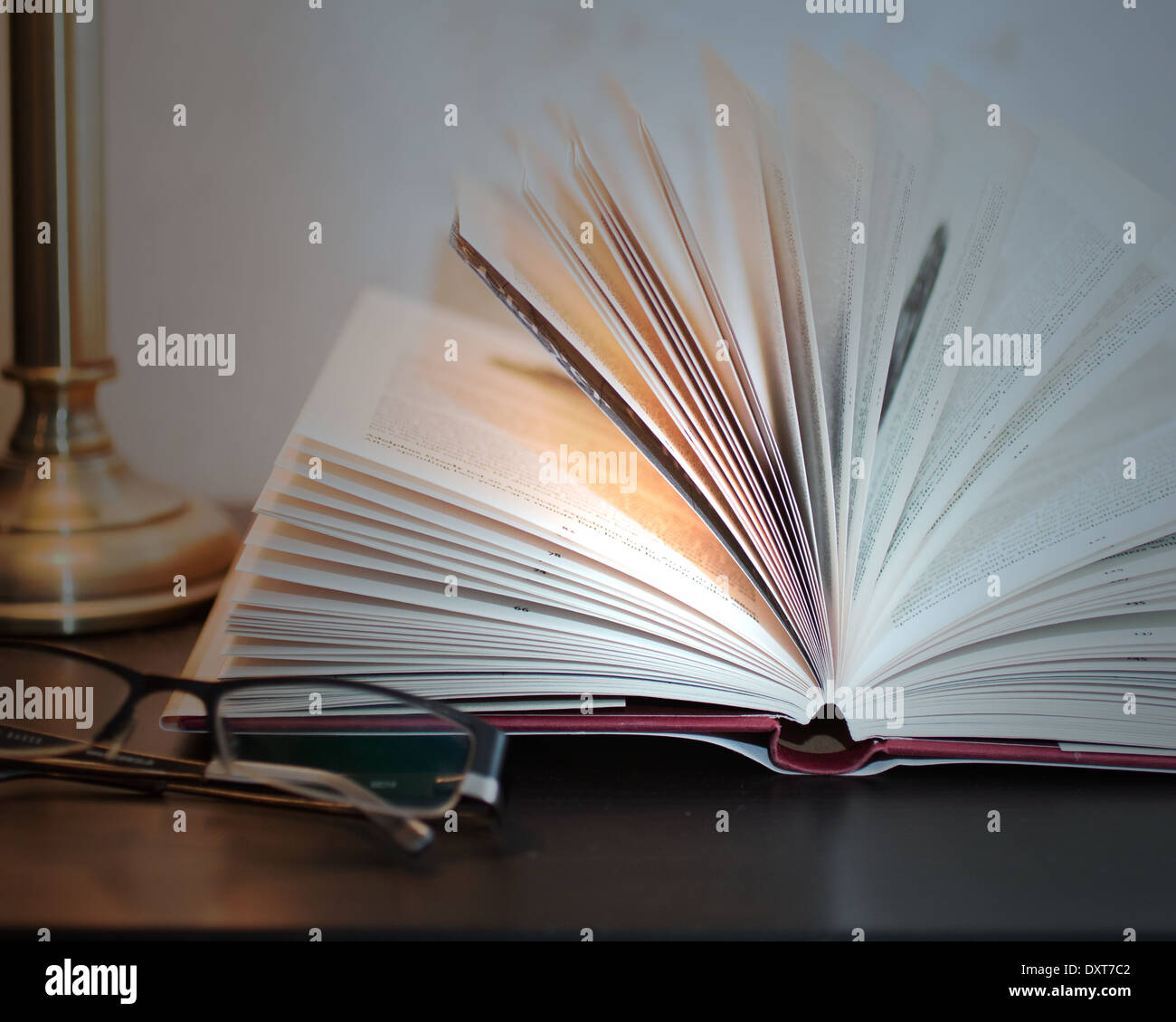 Open book and spectacles on a bedside table Stock Photo - Alamy