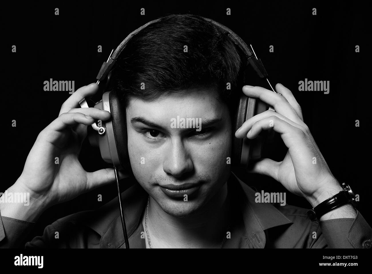 Handsome young man putting on headphones Stock Photo - Alamy
