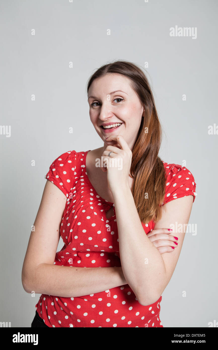 Studio portrait of smiling attractive woman with folded arms and hand ...