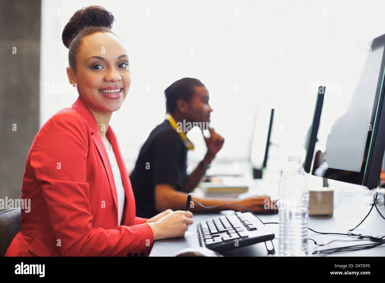 Happy young african american woman sitting in front of computer smiling ...